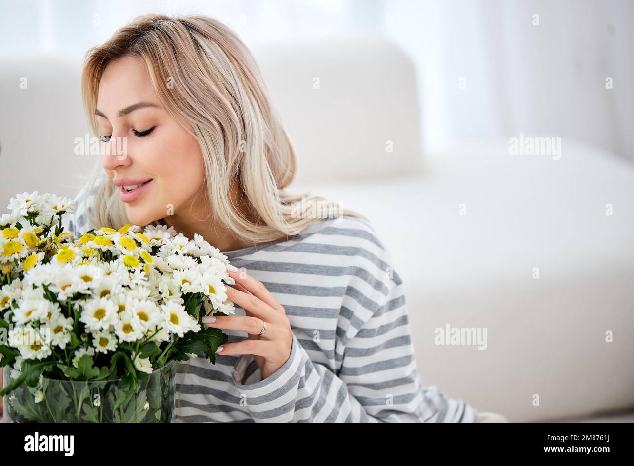 charming woman with wildflowers at home with a delicate smile on face ...