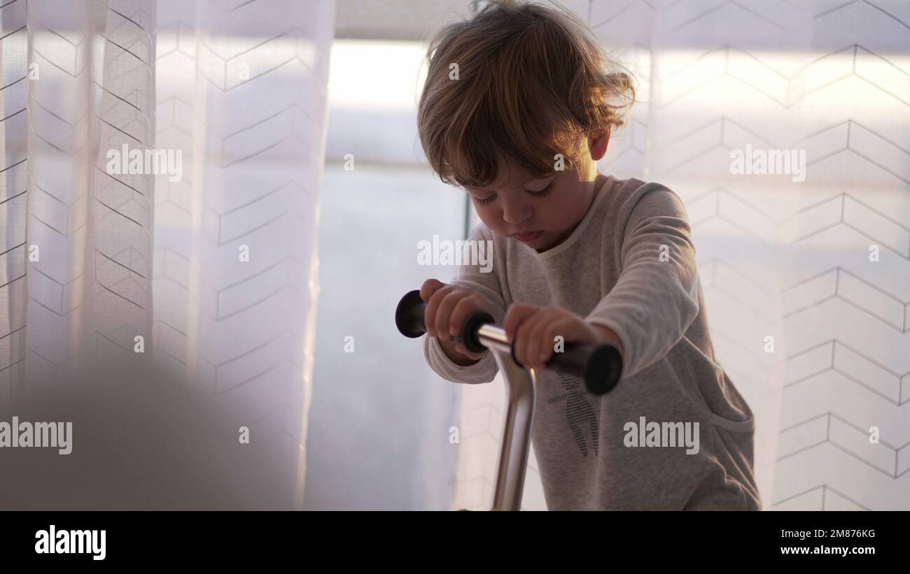 Toddler boy standing on toy scooter Stock Photo - Alamy