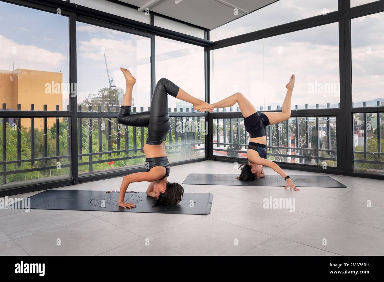 Couple of young women doing yoga poses together in front of studio ...