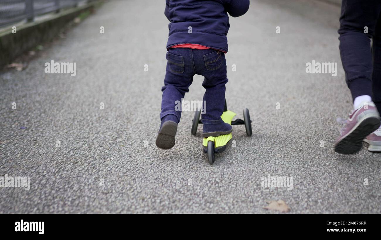 Toddler child riding three wheeled toy scooter at park Stock Photo - Alamy