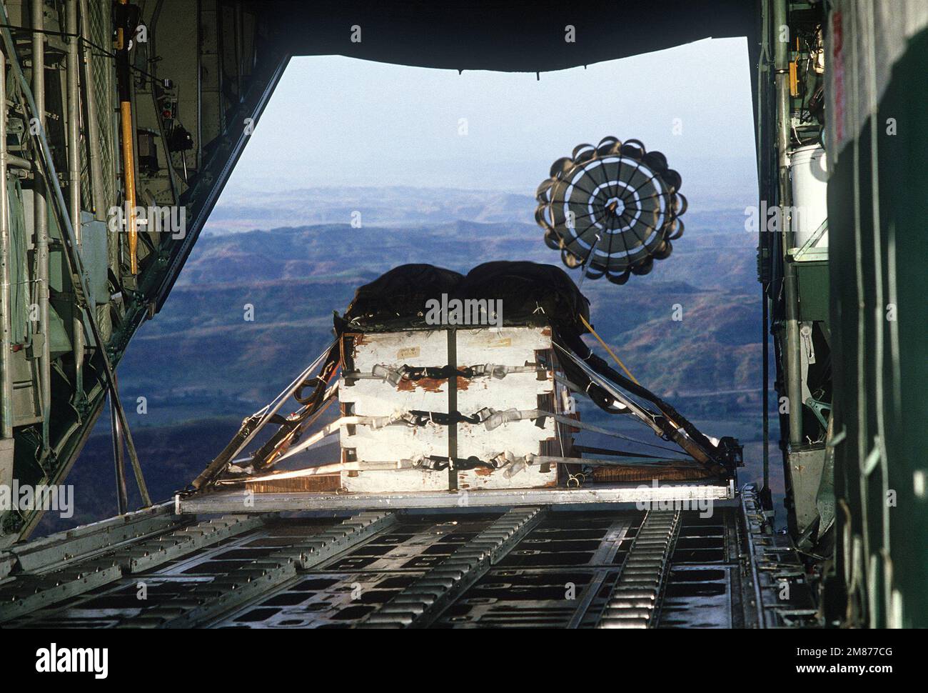 A pallet loaded with heavy cargo is airdropped from a C-130 Hercules ...