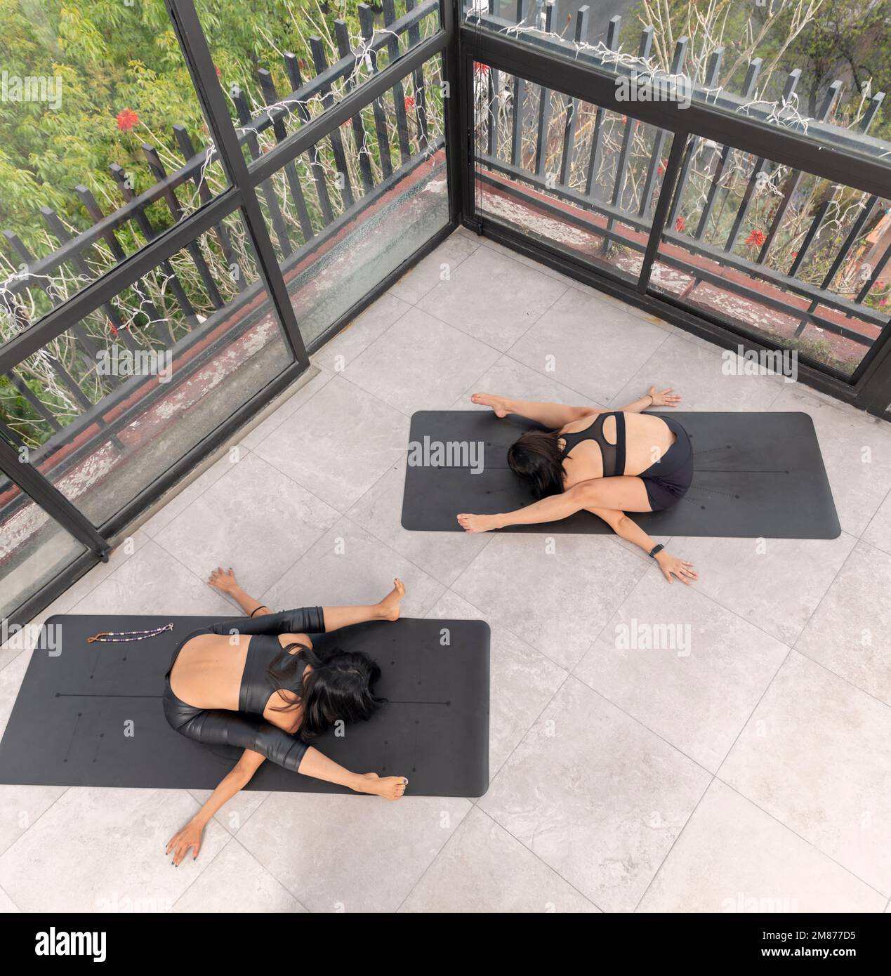 Two attractive women doing yoga kurmasana posture in studio, on the ...