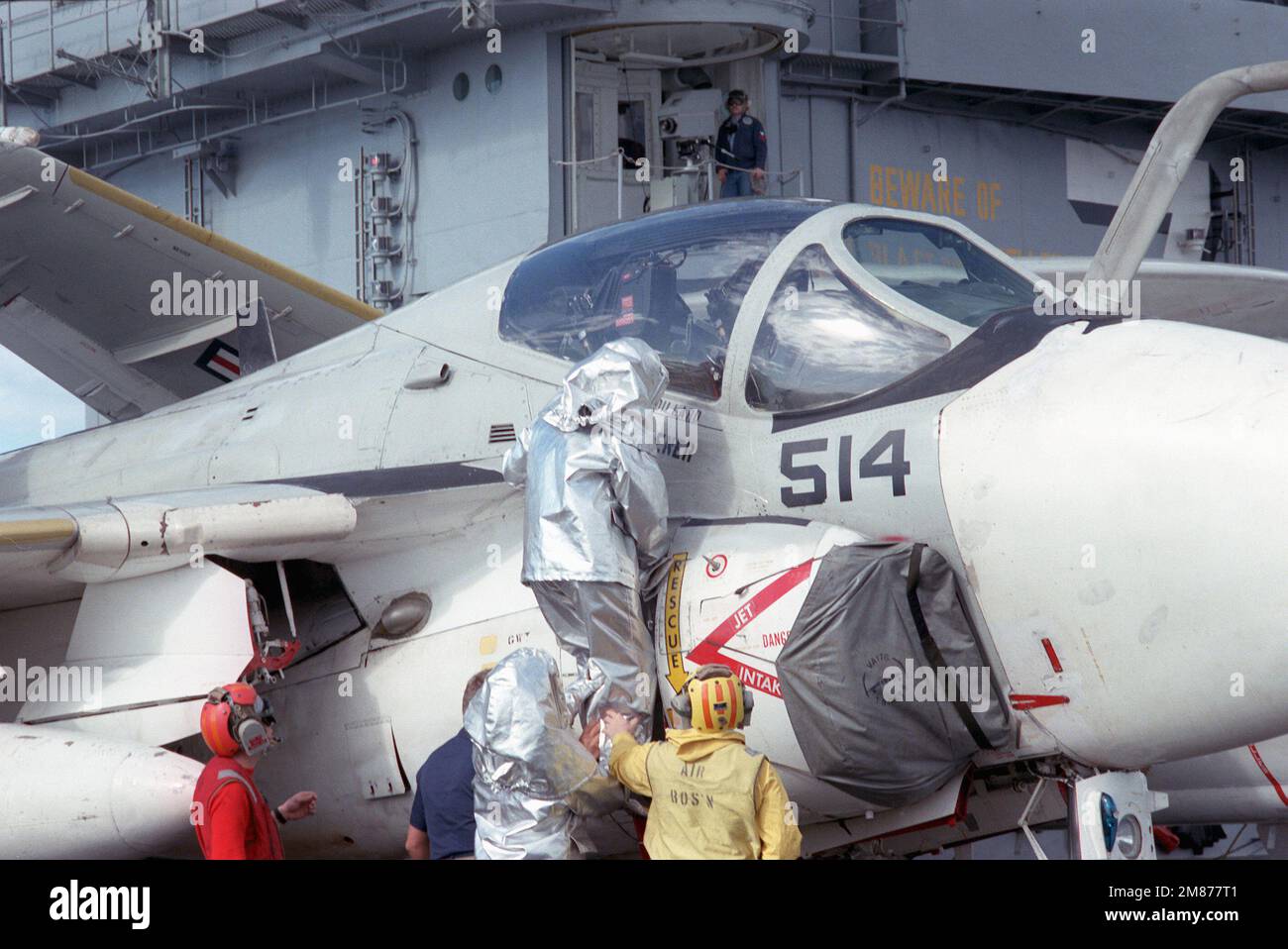 A firefighter wearing a proximity suit climbs onto an A-6E Intruder ...