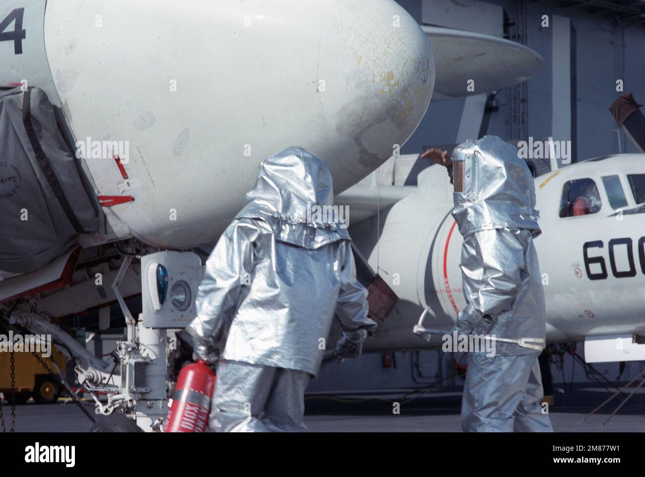 Firefighters wearing proximity suits approach an A-6E Intruder aircraft ...