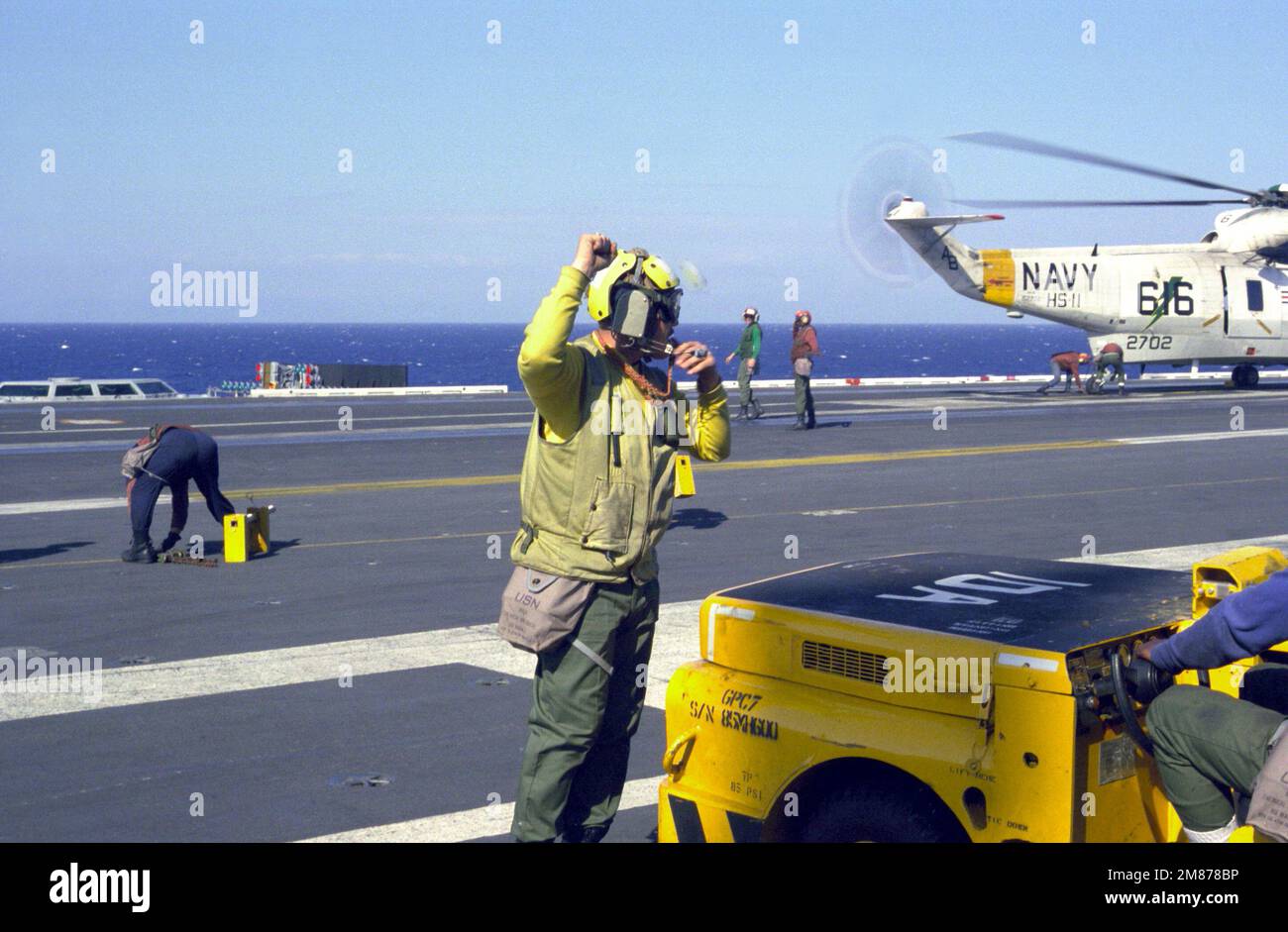 A flight deck crewman signals as he directs the movement of aircraft on ...