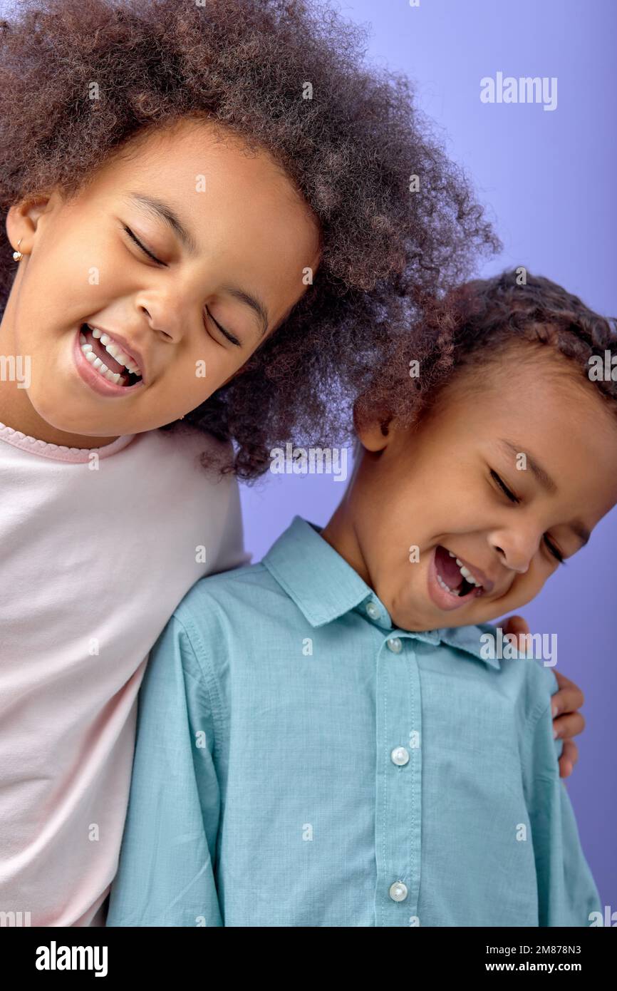 Two joyful black sister and brother having fun while standing isolated ...