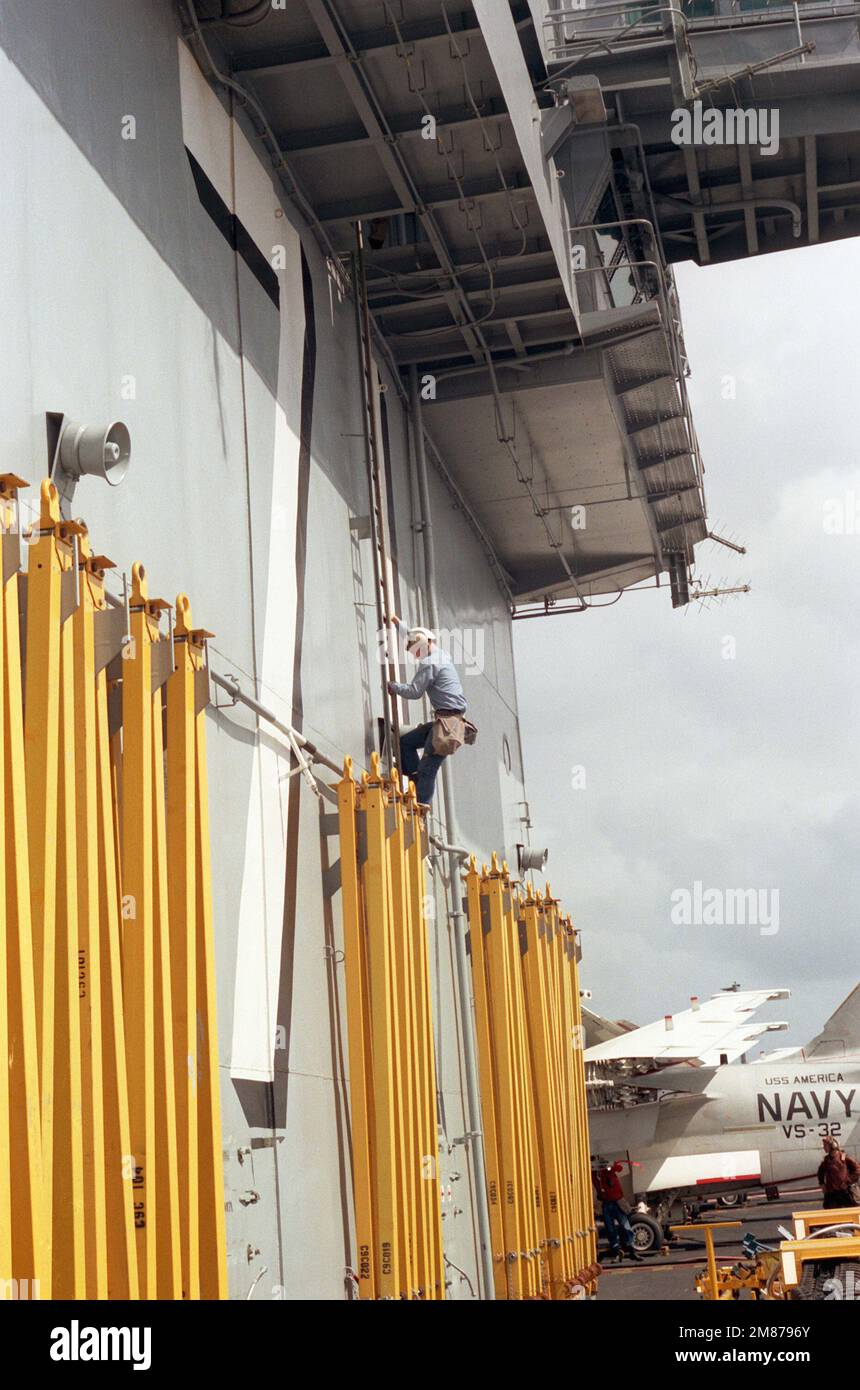 A sailor descends a ladder to the flight deck of the nuclear-powered ...