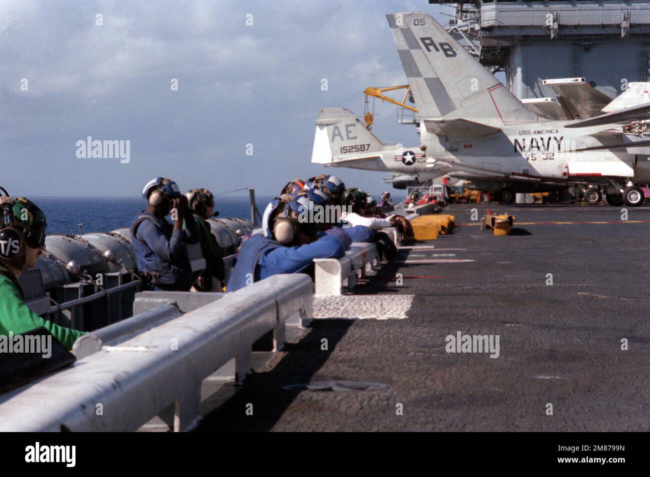 Flight deck crew members stand on the deck edge catwalk of the nuclear ...