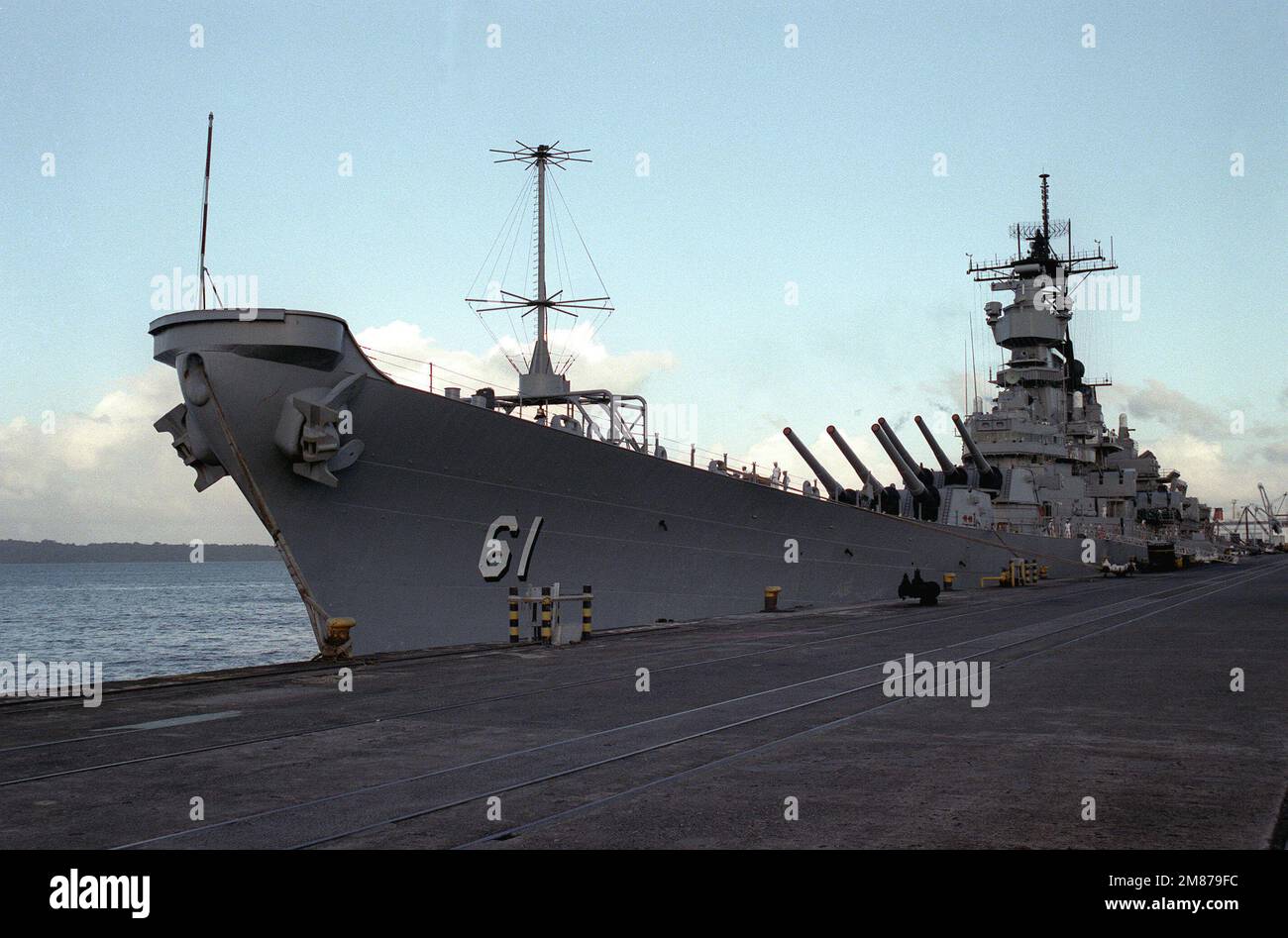 A port bow view of the battleship USS IOWA (BB-61) tied up at a pier. Country: Honduras (HND ...