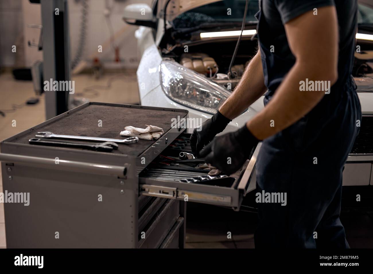 cropped Mechanic in car workshop taking working tools from shelf ...
