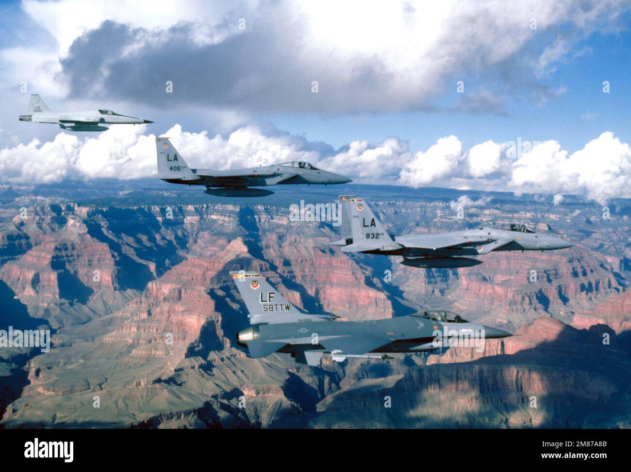 Air to air left side view of a flight of two F-15 Eagles and one F-16 ...