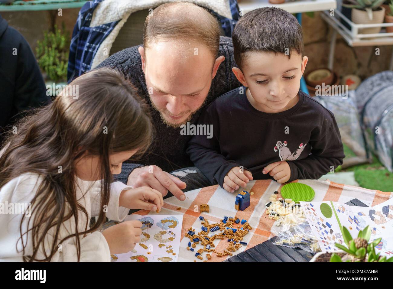 Little Boy And Girl And Young Man Playing With Building Bricks. Father ...
