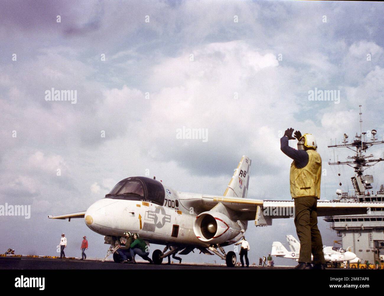 A plane director signals instructions to the pilot of an S-3A Viking as ...