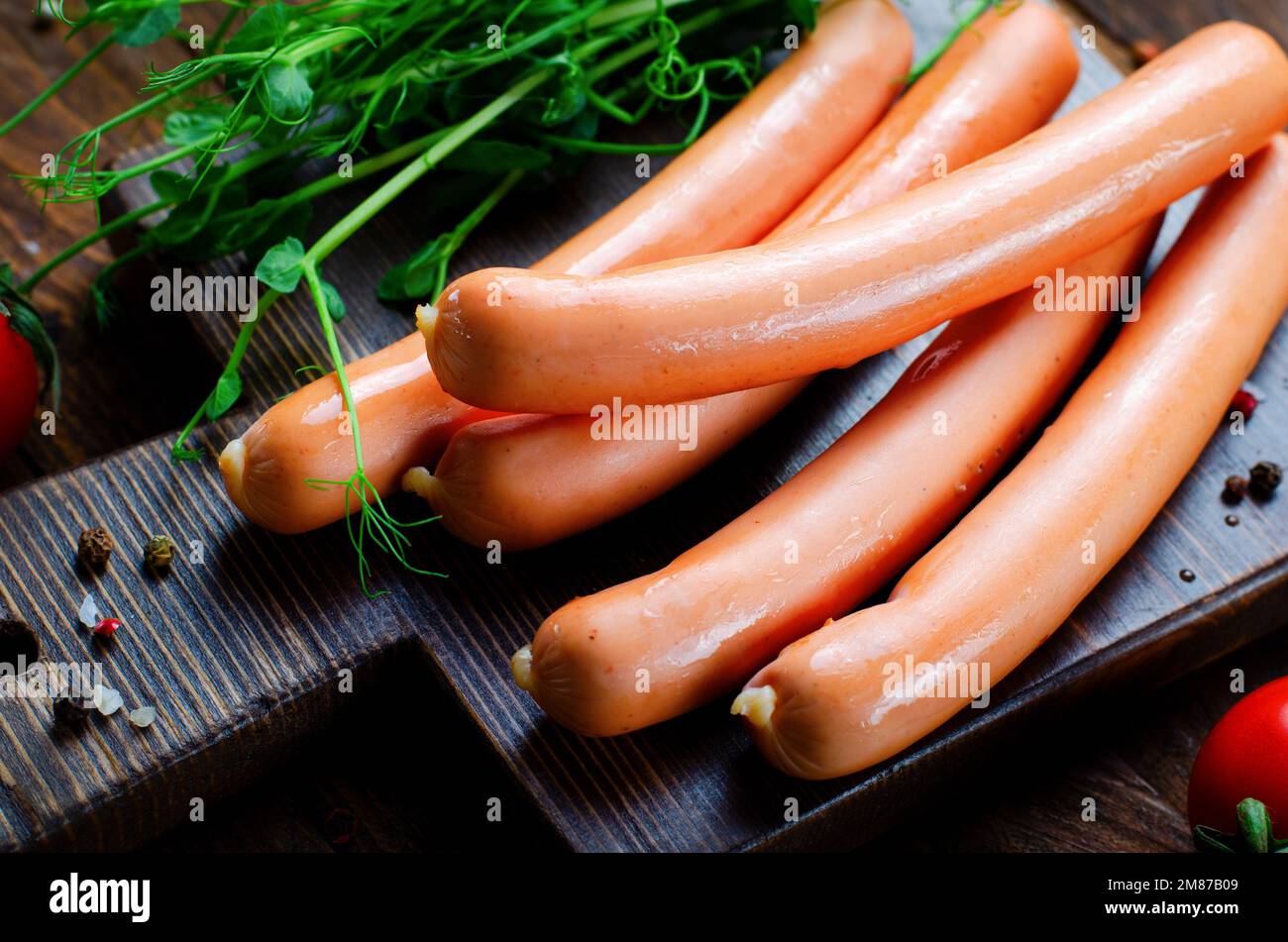Classic Sausages on Wooden Board with herbs and cherry tomatoes on dark ...
