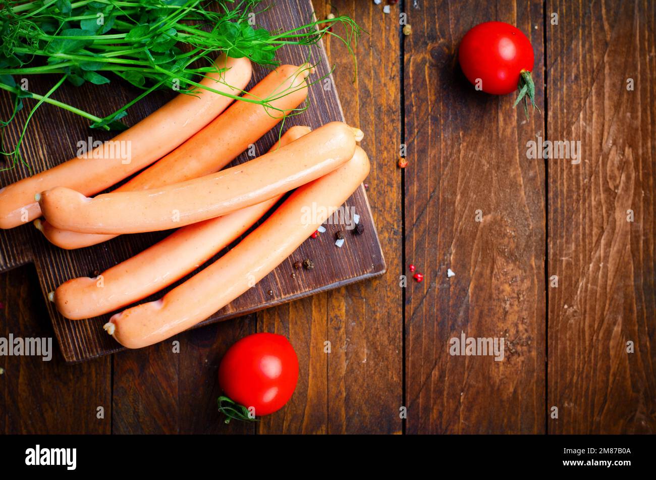 Classic Sausages on Wooden Board with herbs and cherry tomatoes on dark ...