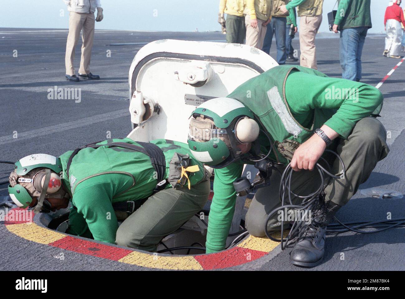 Two crewmen work on a jet blast deflector control box on the flight ...