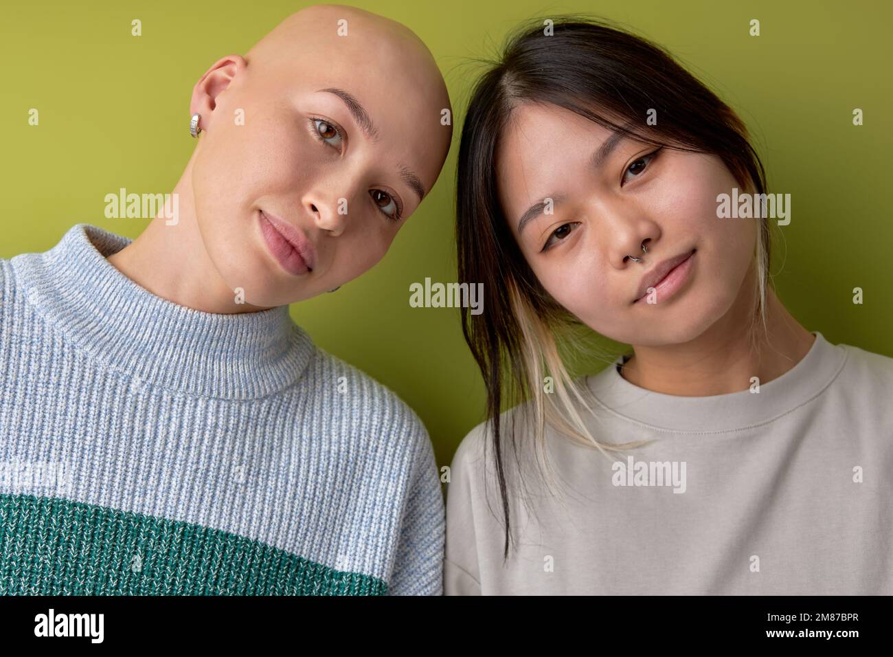 two women posing at camera supporting each other, asian and another ...