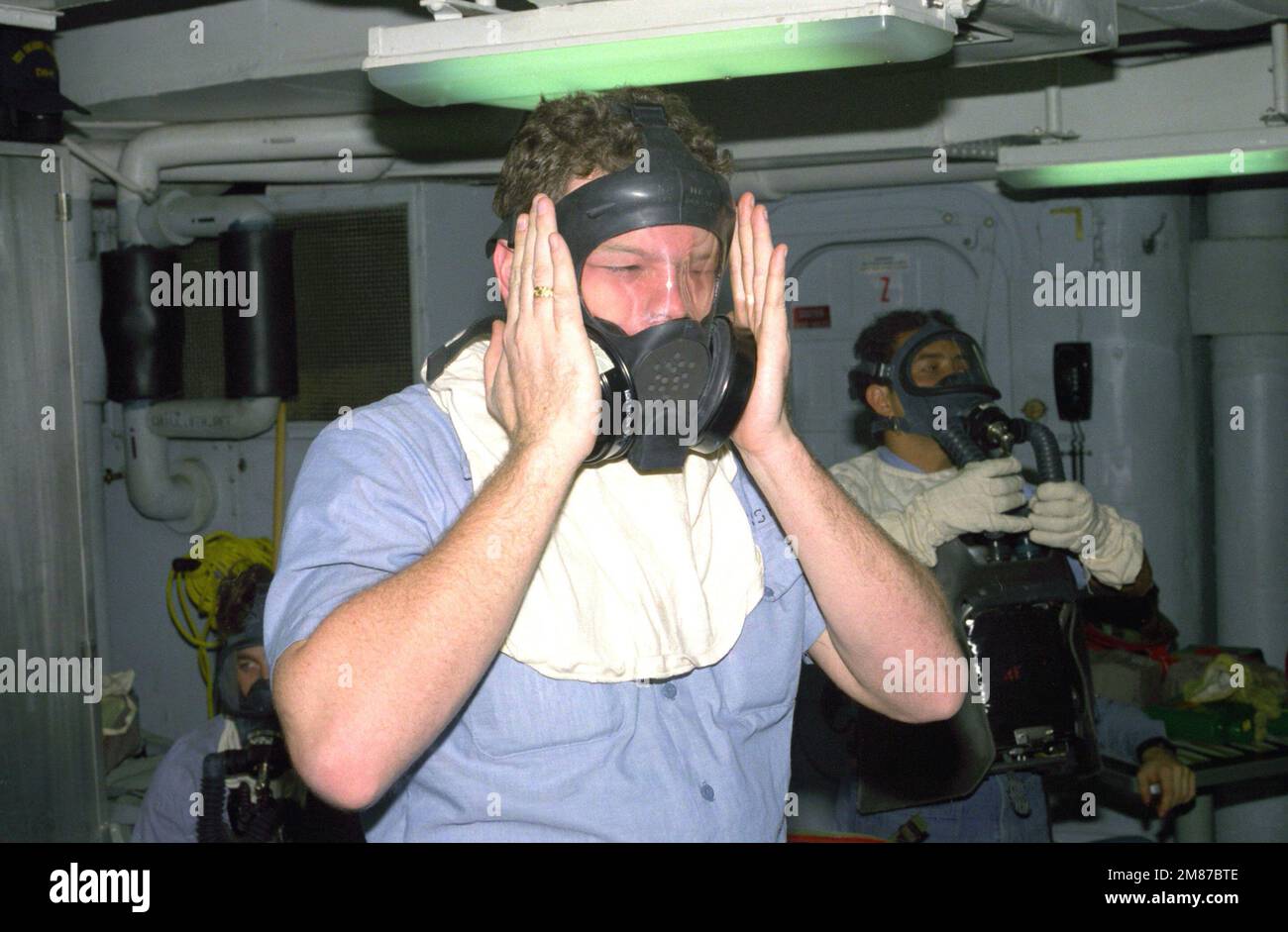 A sailor clears his Mark 5 protective mask during a general quarters ...