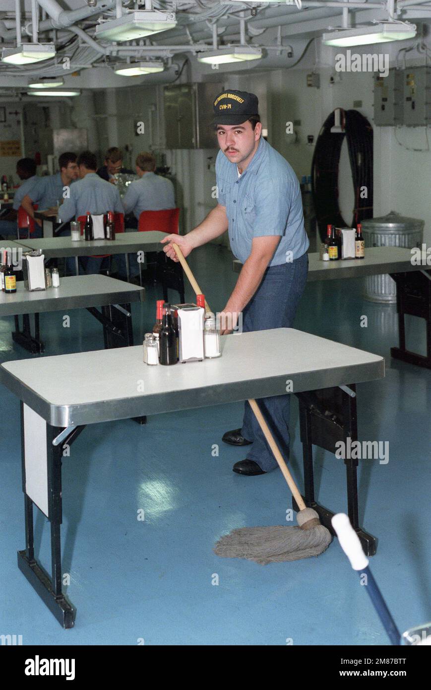 A crew member swabs the mess deck aboard the nuclear-powered aircraft ...