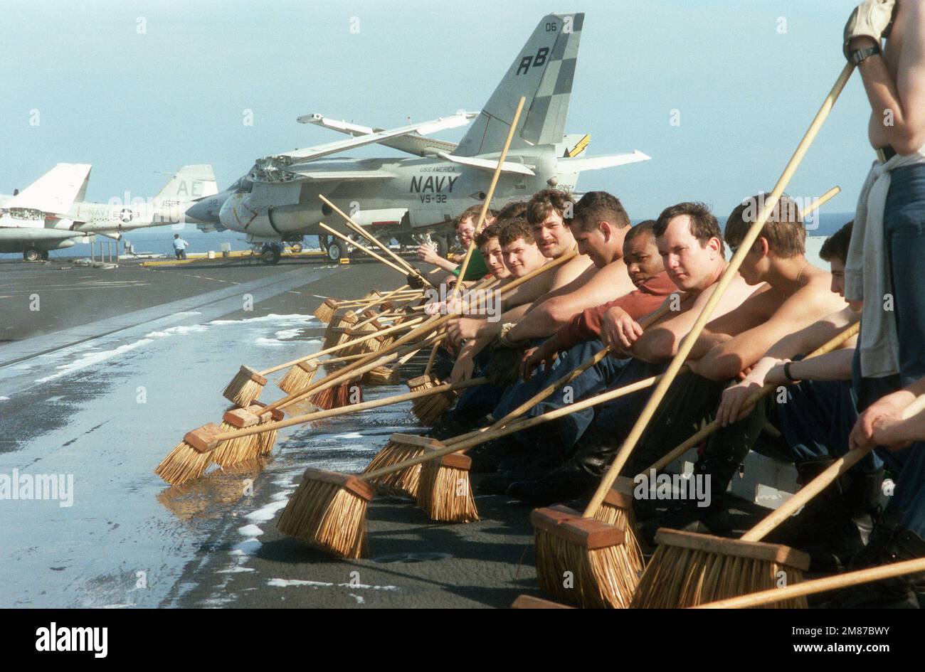 Crewmen take a break from their task of scrubbing the flight deck of ...
