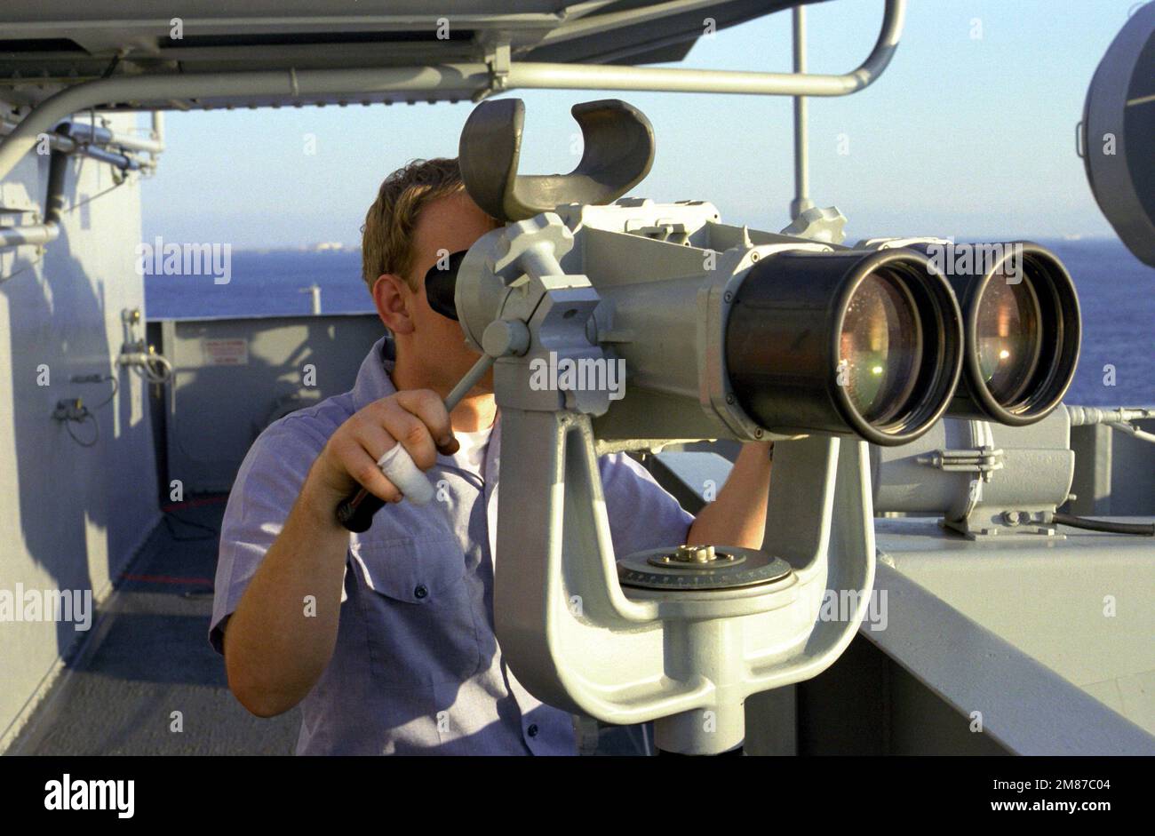 A crewman looks through the ship's binoculars aboard the nuclear-powered aircraft carrier USS ...