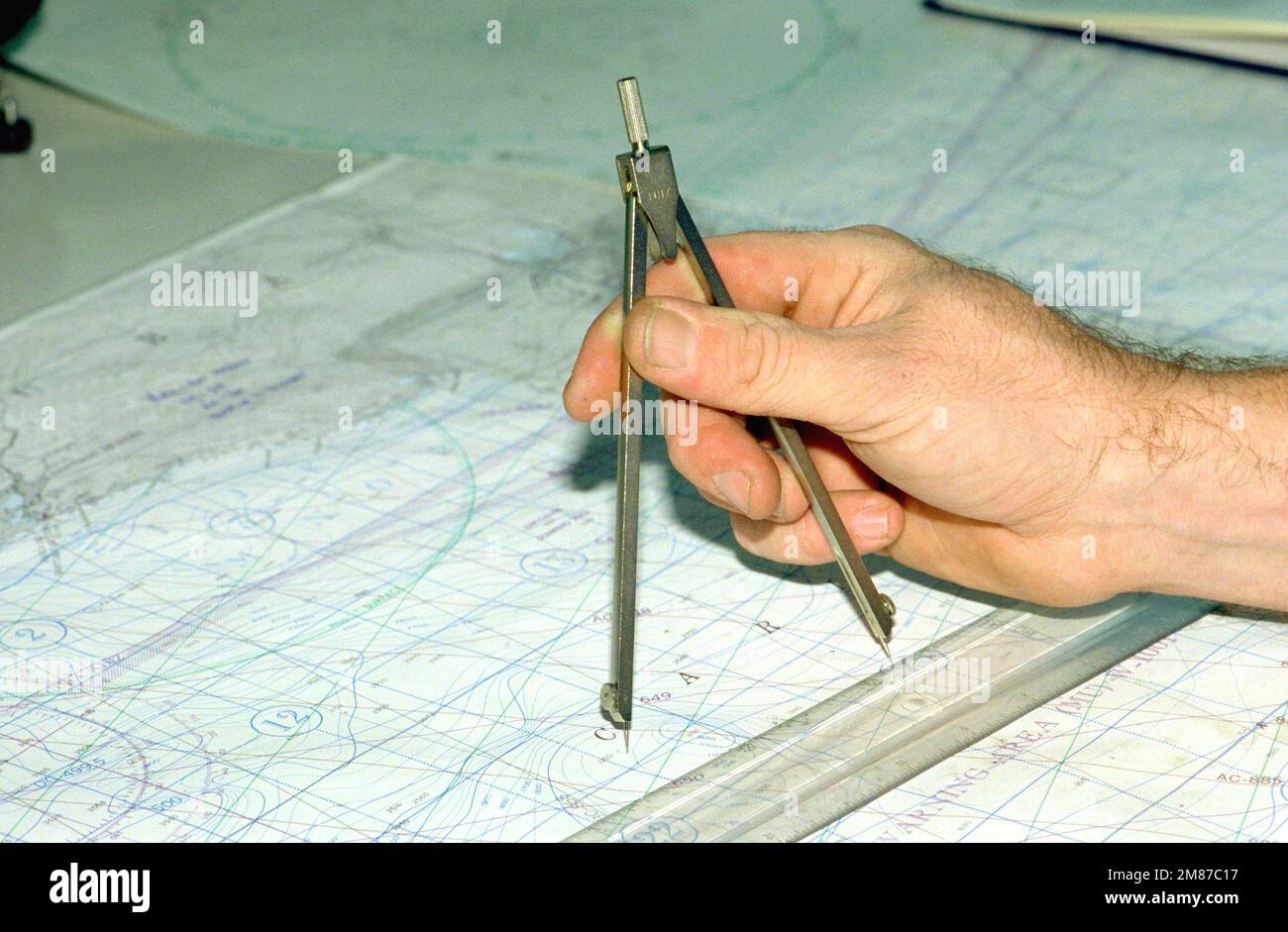 A close-up view of dividers being used to gauge distance on a chart on ...