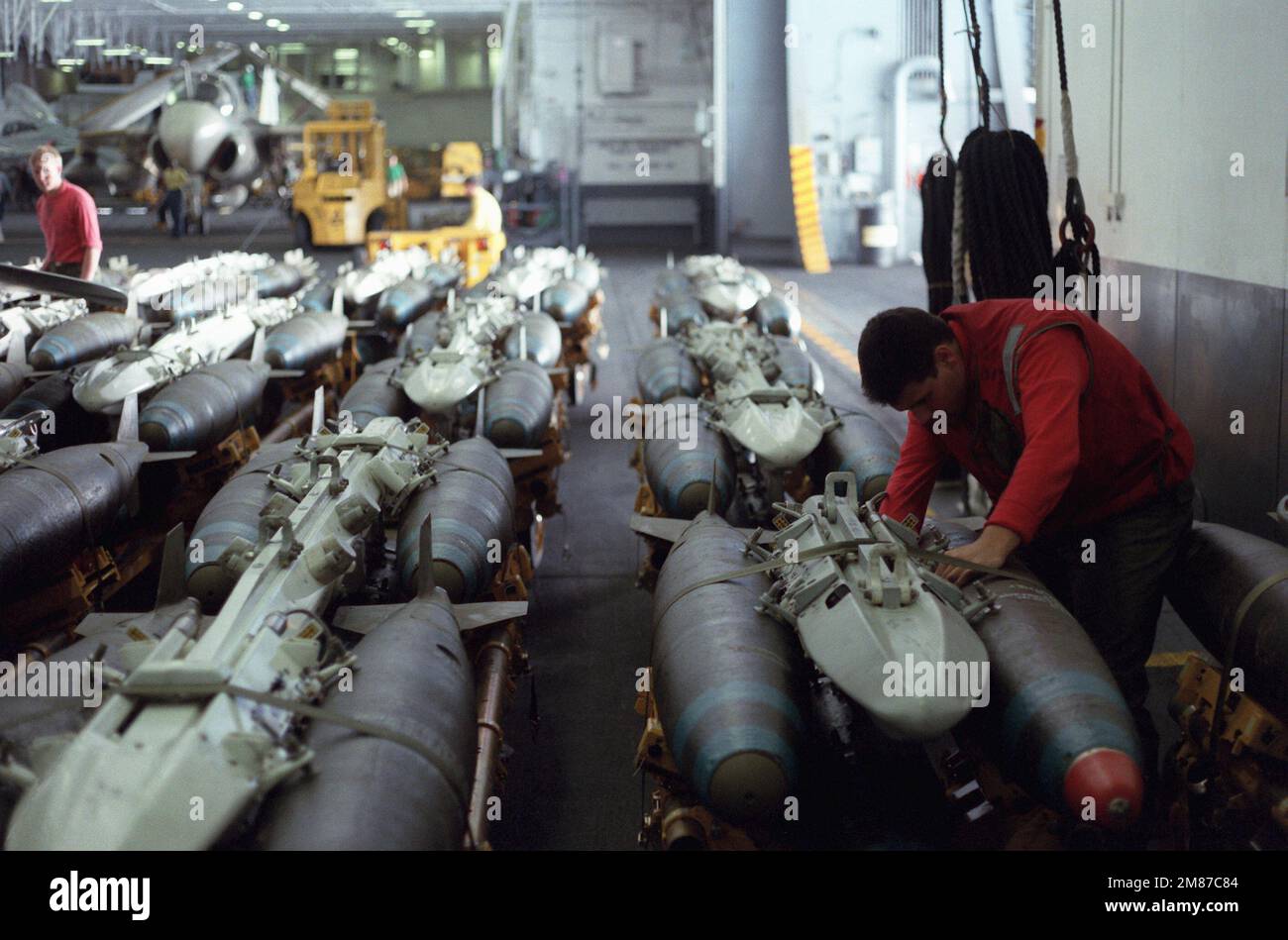 A sailor from the ship's G-1 Division ensures a load of Mark 82 general ...