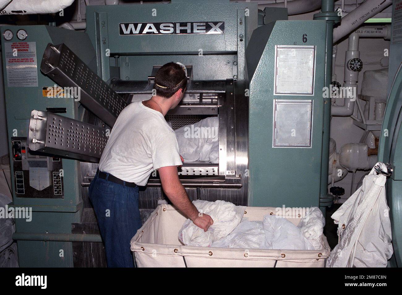 A sailor unloads a washing machine aboard the nuclear-powered aircraft ...