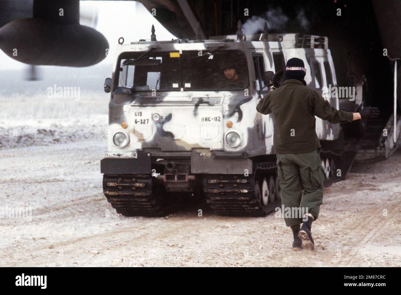 An airman guides an M-973 small unit support vehicle out of a C-130 ...