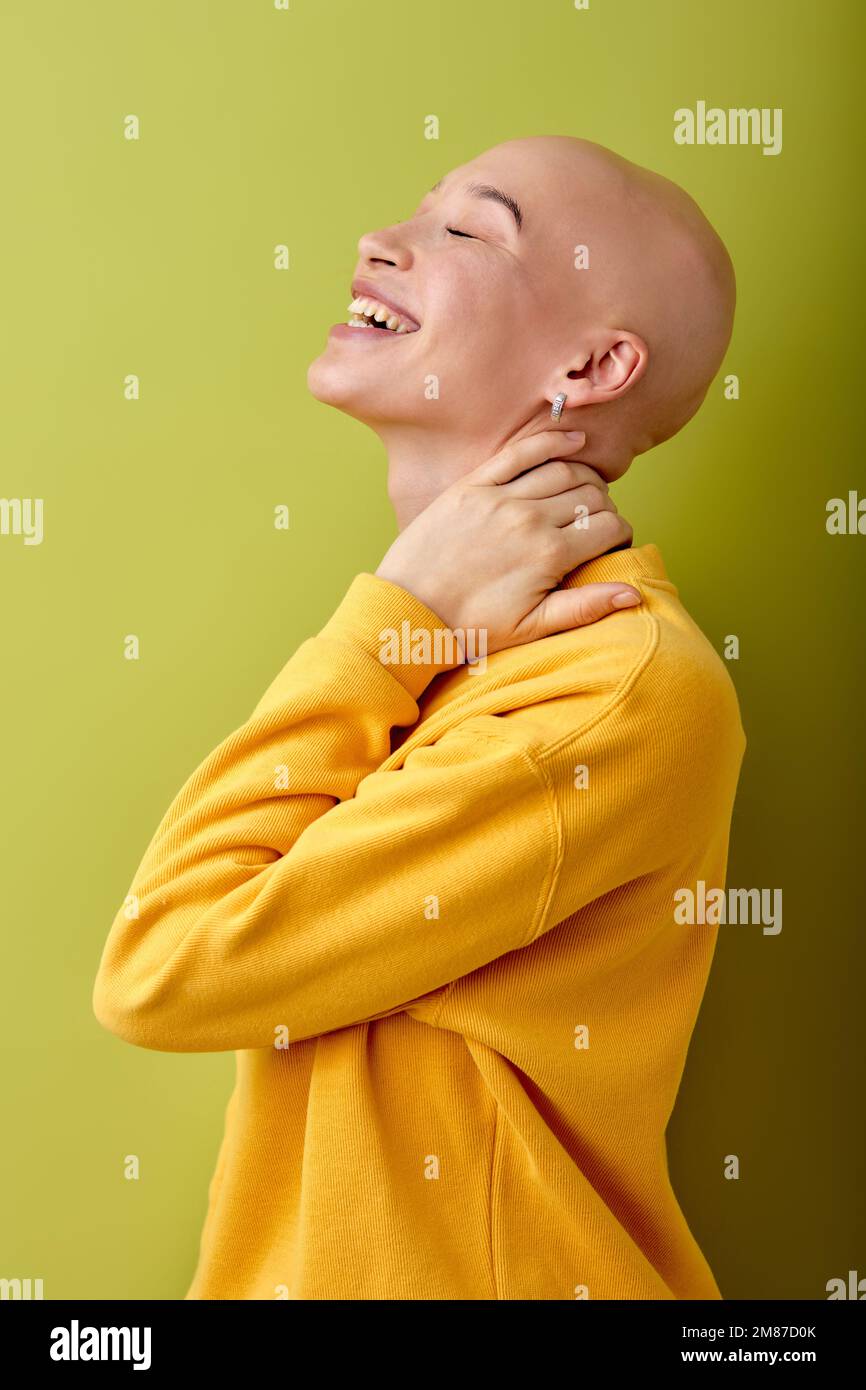 Portrait of young caucasian bald woman isolated on green studio ...