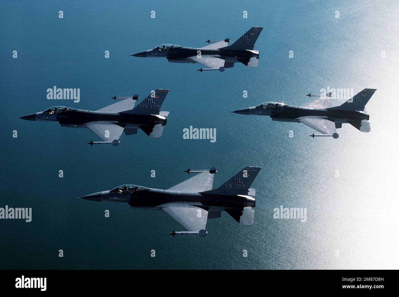 An air-to-air left side view of four F-16 Fighting Falcon aircraft of ...