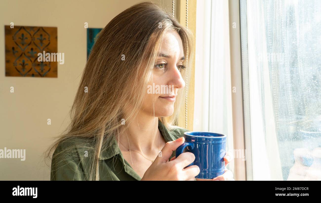 Young adult woman feeling blue. Stressful woman watching outside by the ...