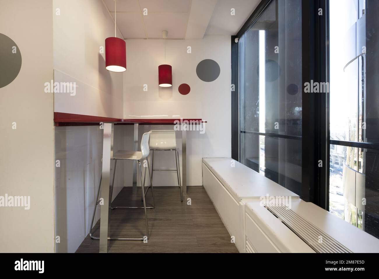 Corner of a coworking kitchen with a red wood eating bar and metal and ...