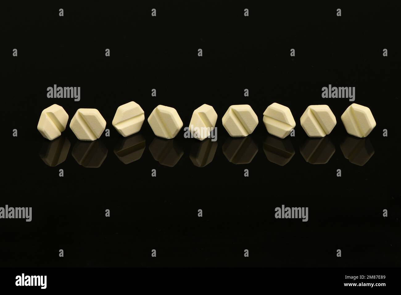 Hexagonal pills on light black acrylic background. Extreme closeup ...
