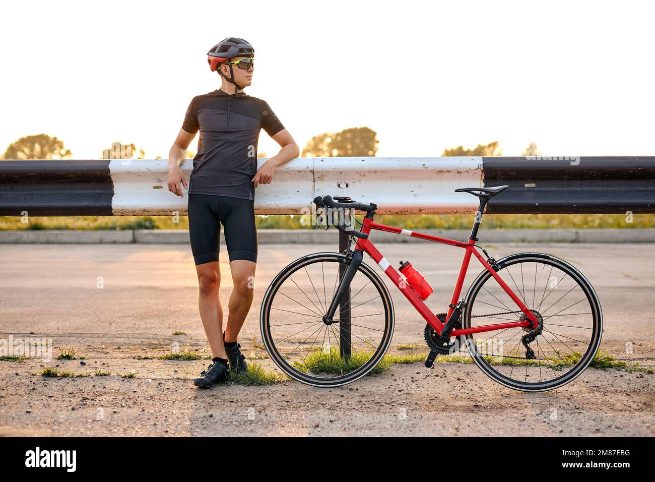 Cyclist in shorts and helmet standing on road in countryside having ...