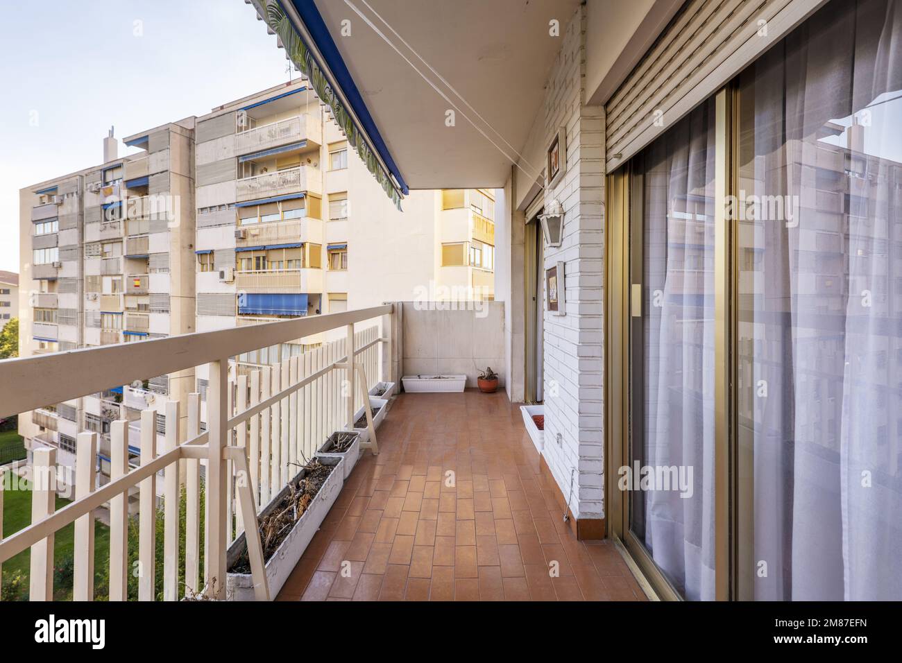 Porch-type terrace of a house with a golden metal railing with pots on ...
