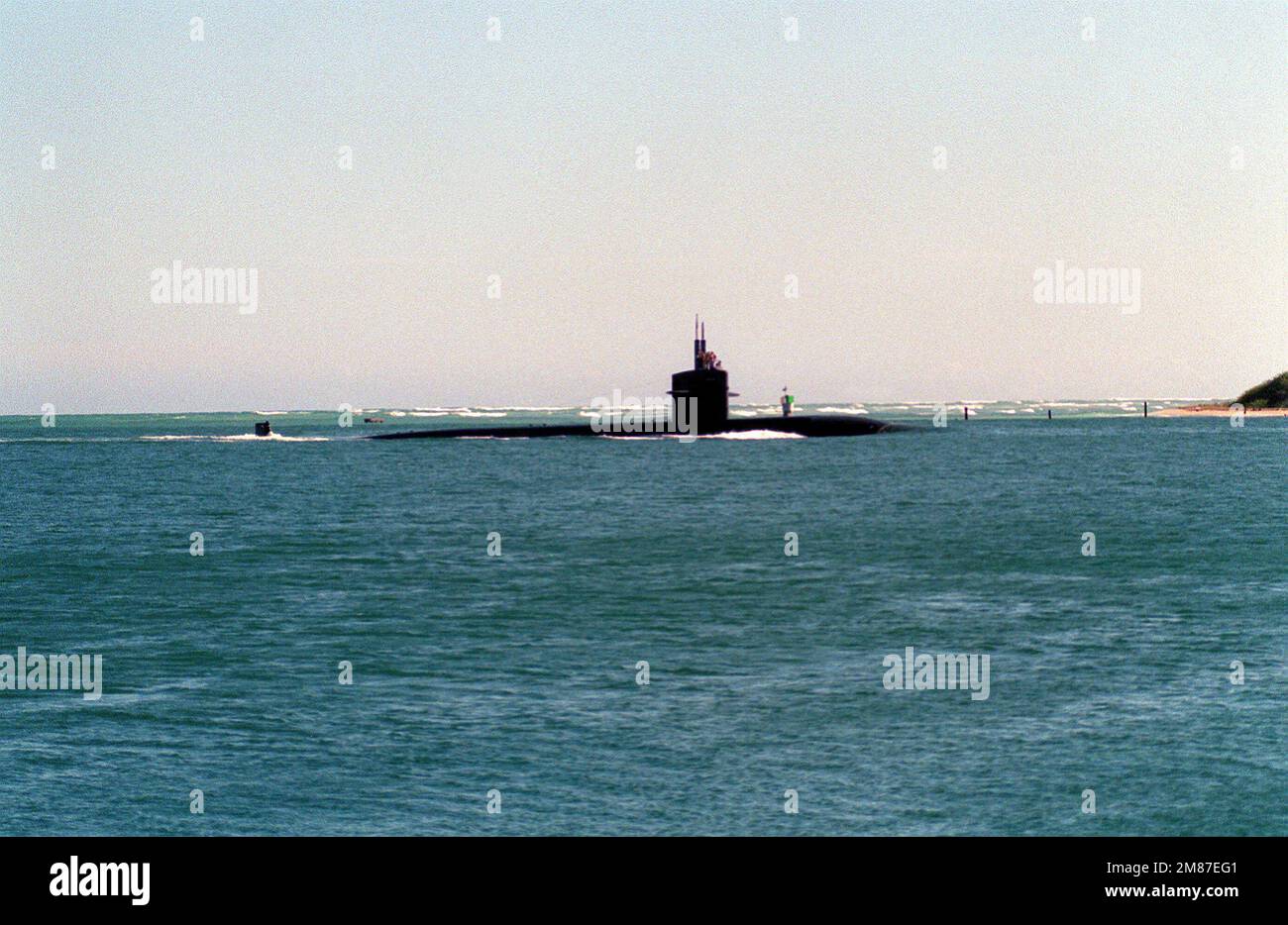 Crew members stand on the sail of the nuclear-powered attack submarine ...