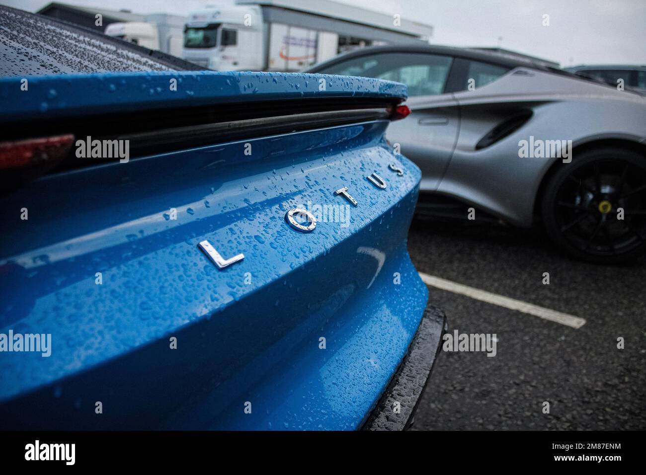 A closeup of the backside of the wet, blue Lotus automobile with a ...