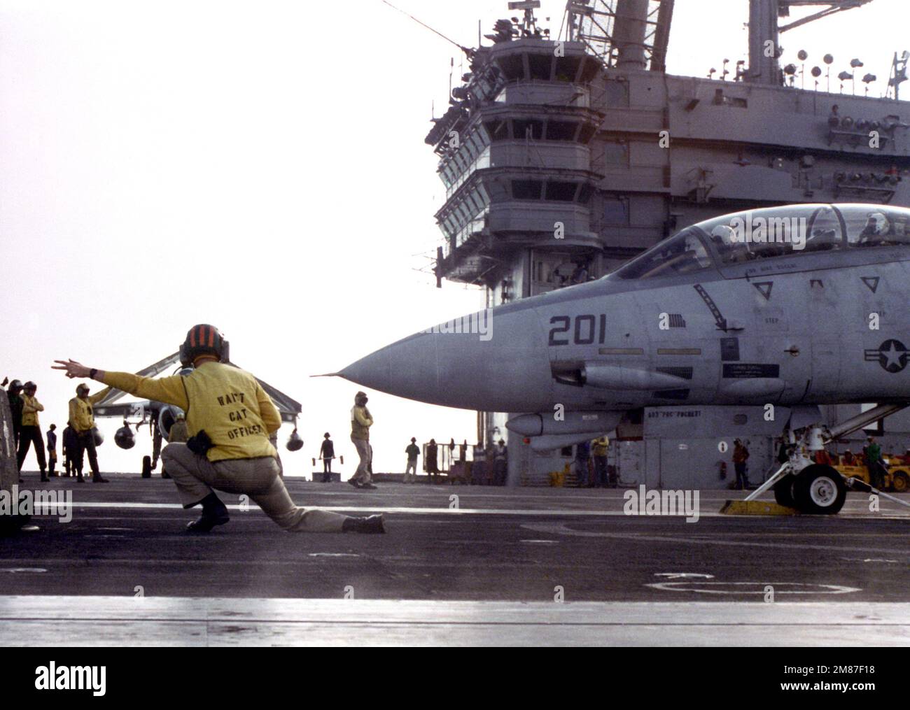 A catapult officer gives the launch signal to the pilot of an F-14A ...