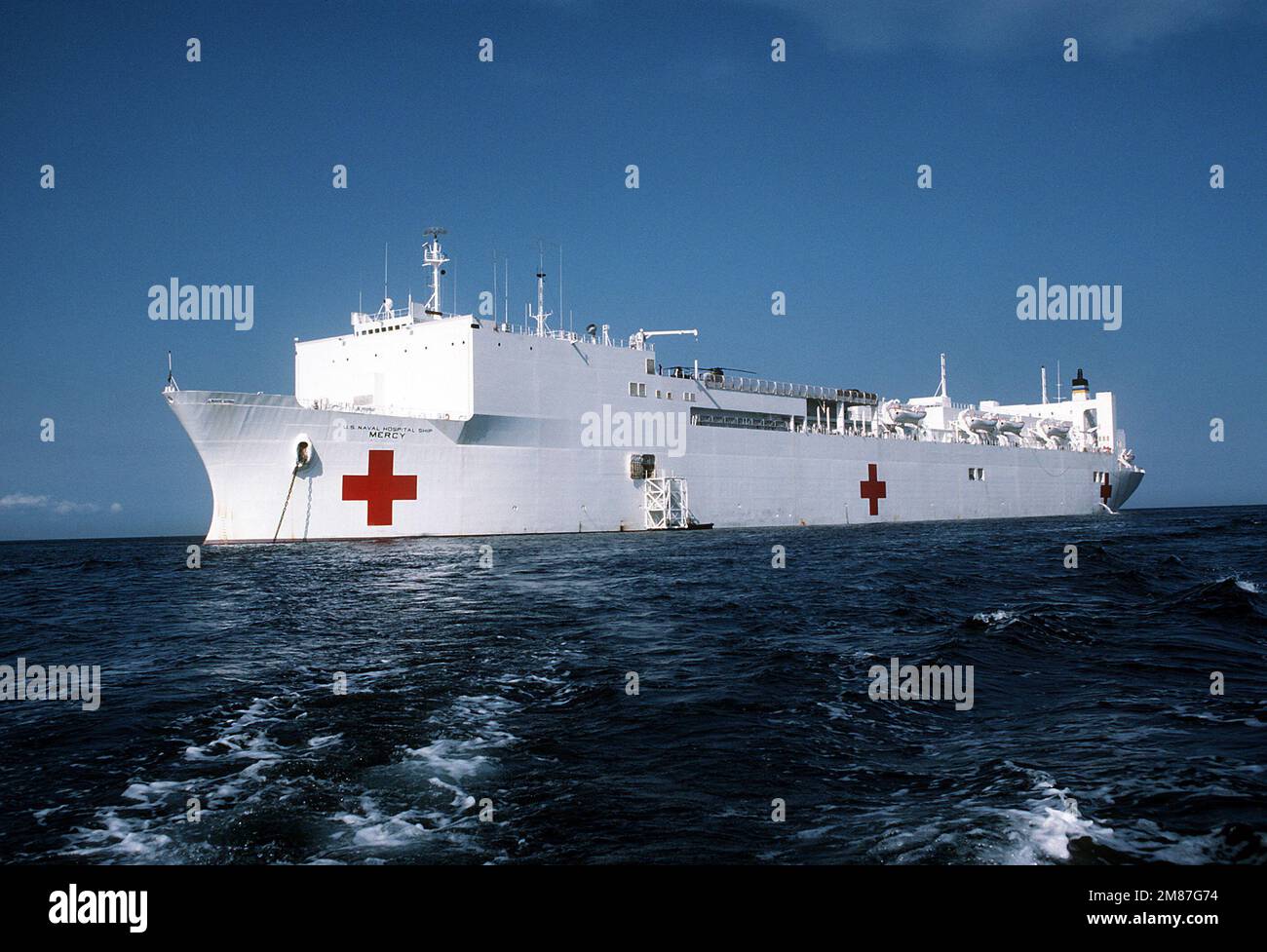 A port bow view of the hospital ship USNS MERCY (T-AH-19) anchored off ...