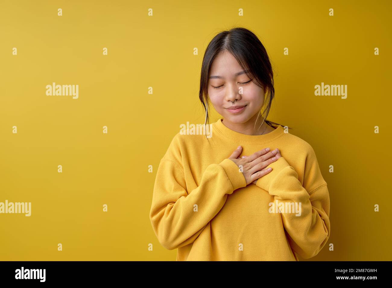 Thankful kind chinese female keeping hands on chest expressing ...