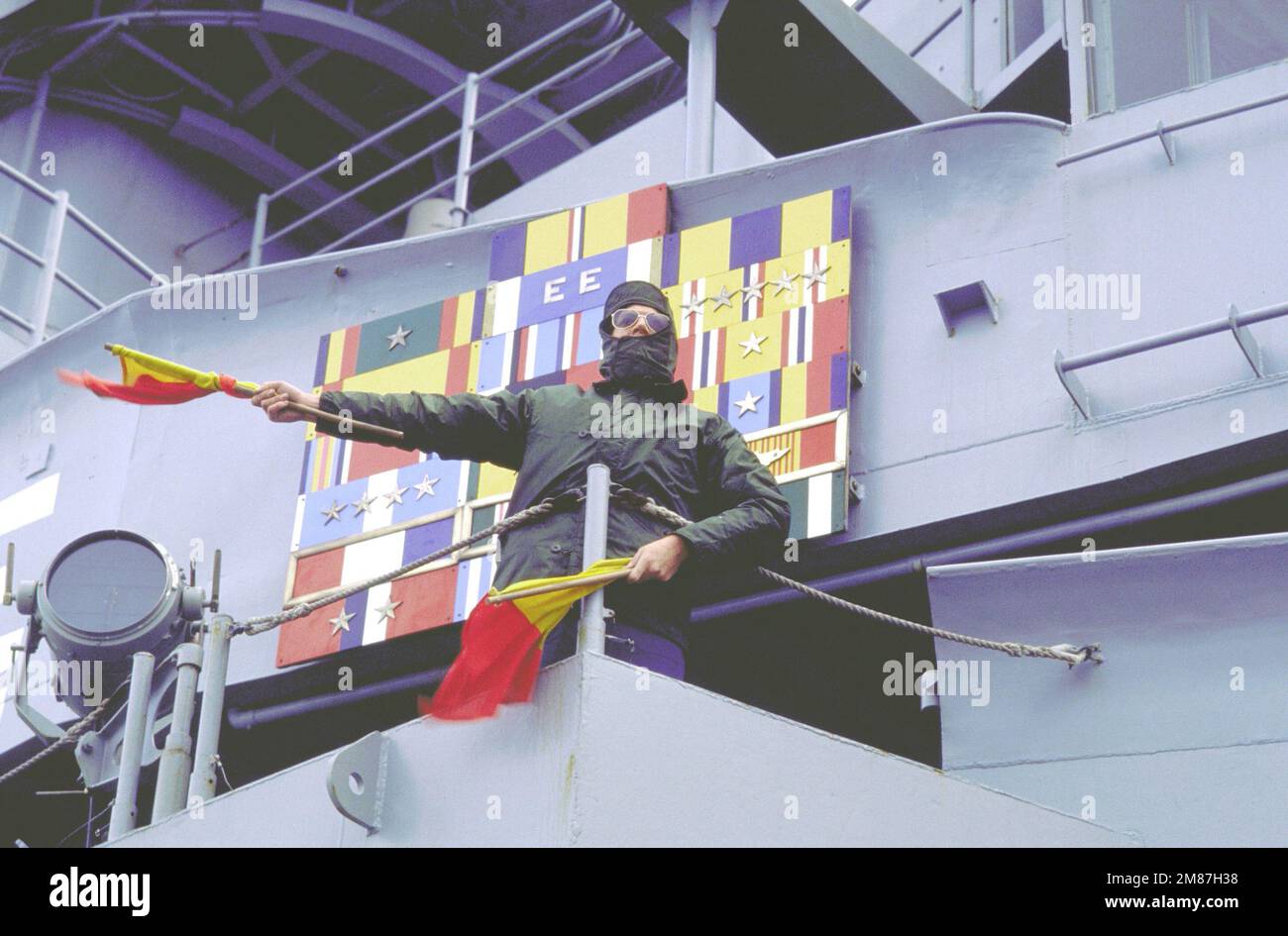 A signalman uses semaphore flags to send a message from the battleship ...