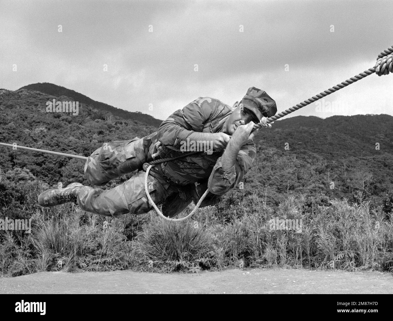A Marine pulls himself along a rope stretched across a stream at the ...