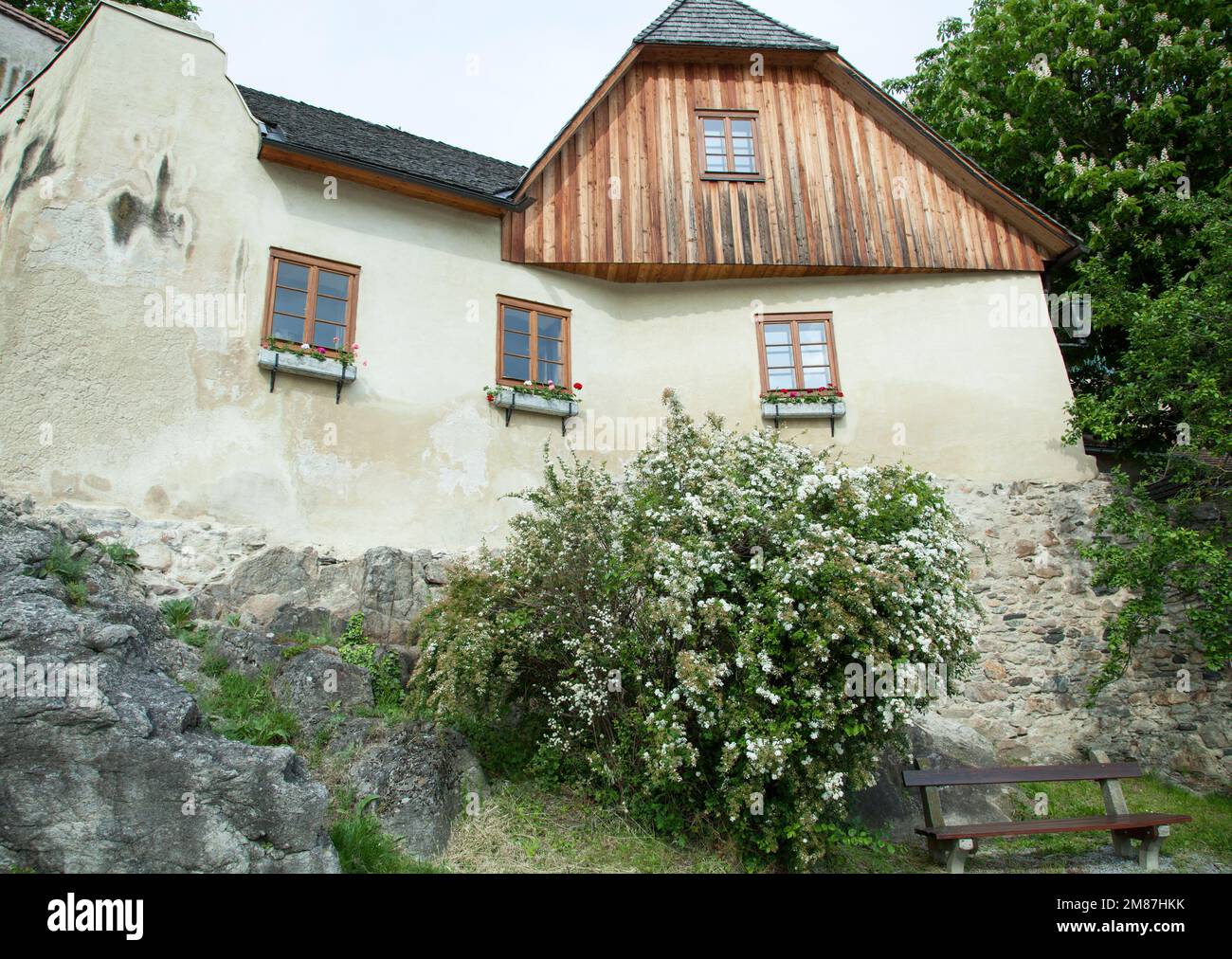 The view of a bench under the plant in blossom and a traditional house ...