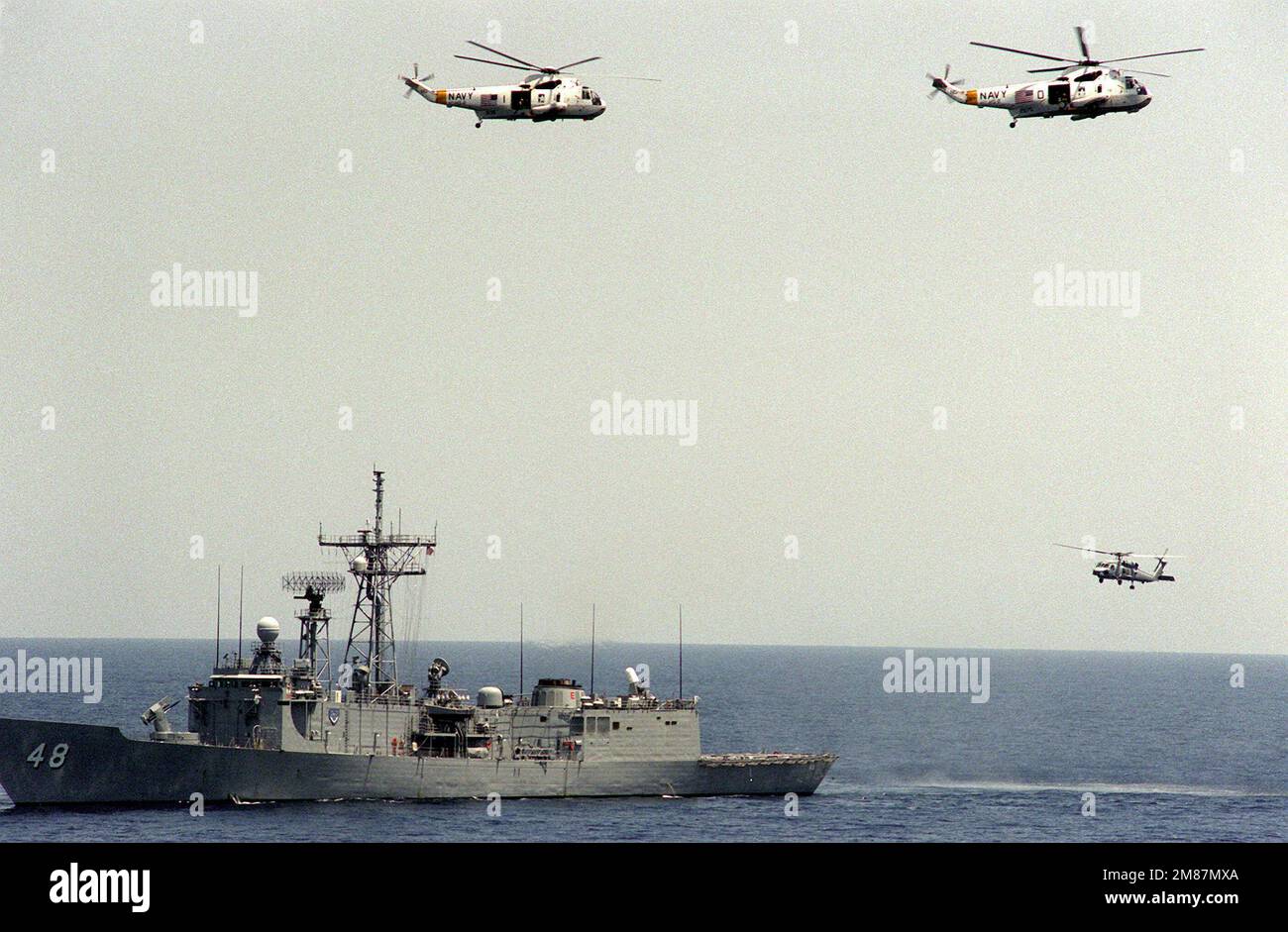 Two SH-3 Sea King helicopters hover above the guided missile frigate ...