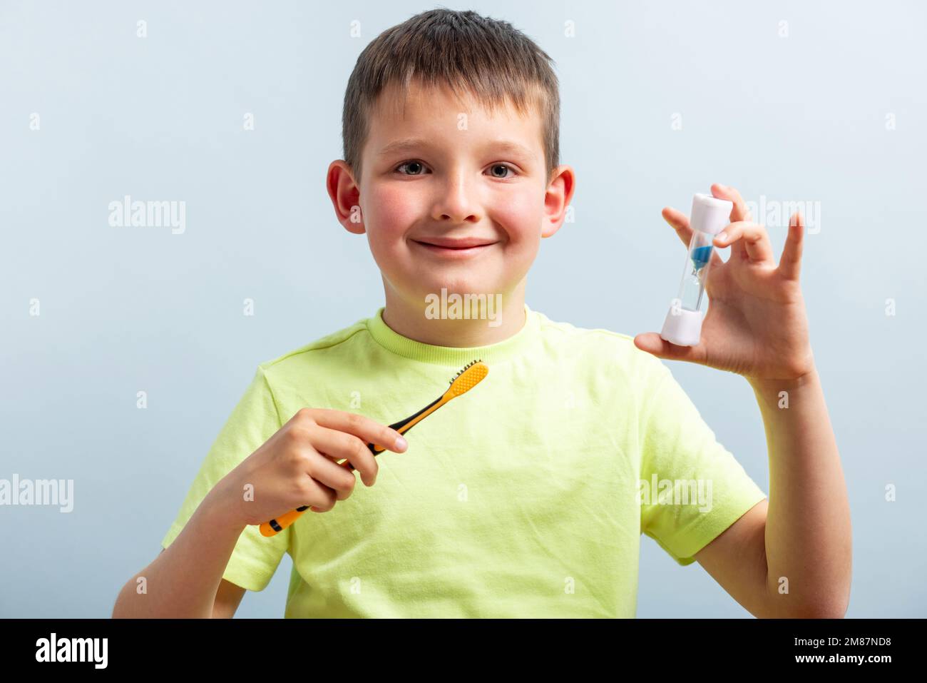 Kid boy with sandglass brushing his teeth on blue background Stock ...