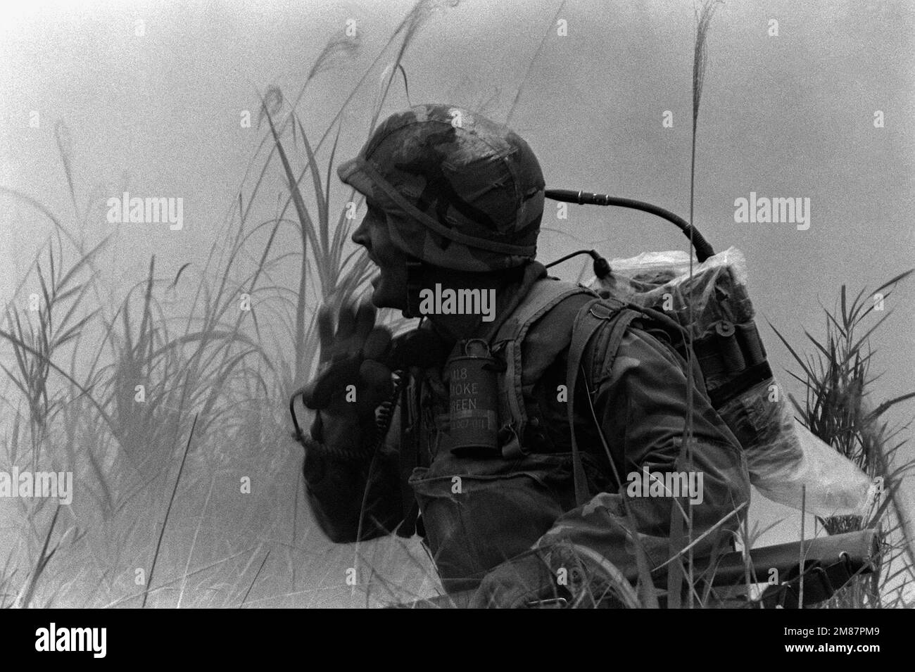 A Marine carrying an AN/PRC-77 field radio shouts to a member of his ...