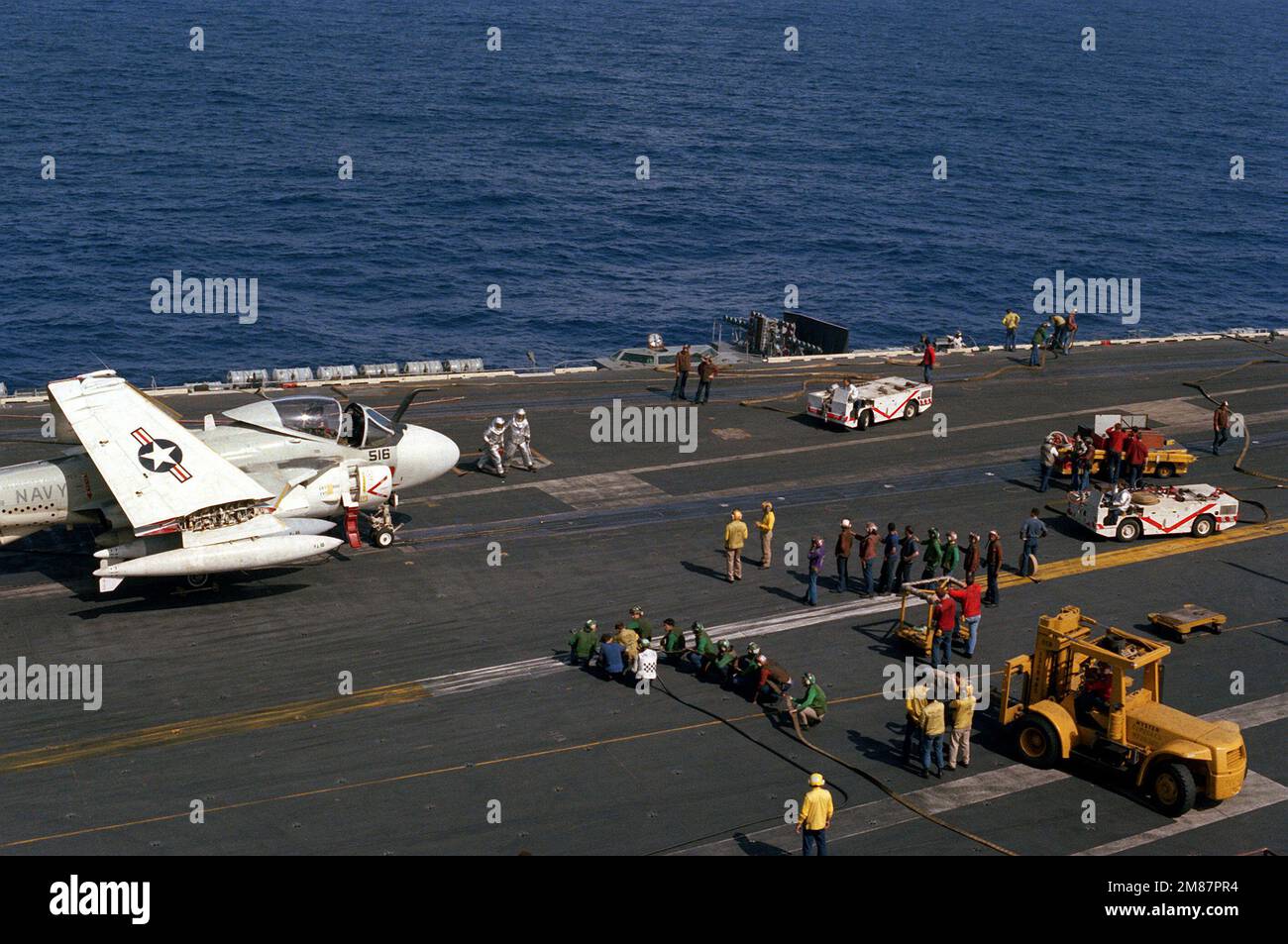 Crew members approach an KA-6D Intruder aircraft with hoses and damage ...