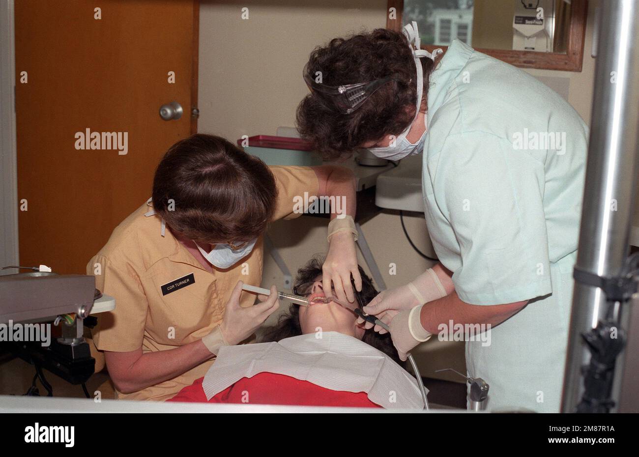At the dental clinic, CMDR. C. Turner gives a patient a shot of ...