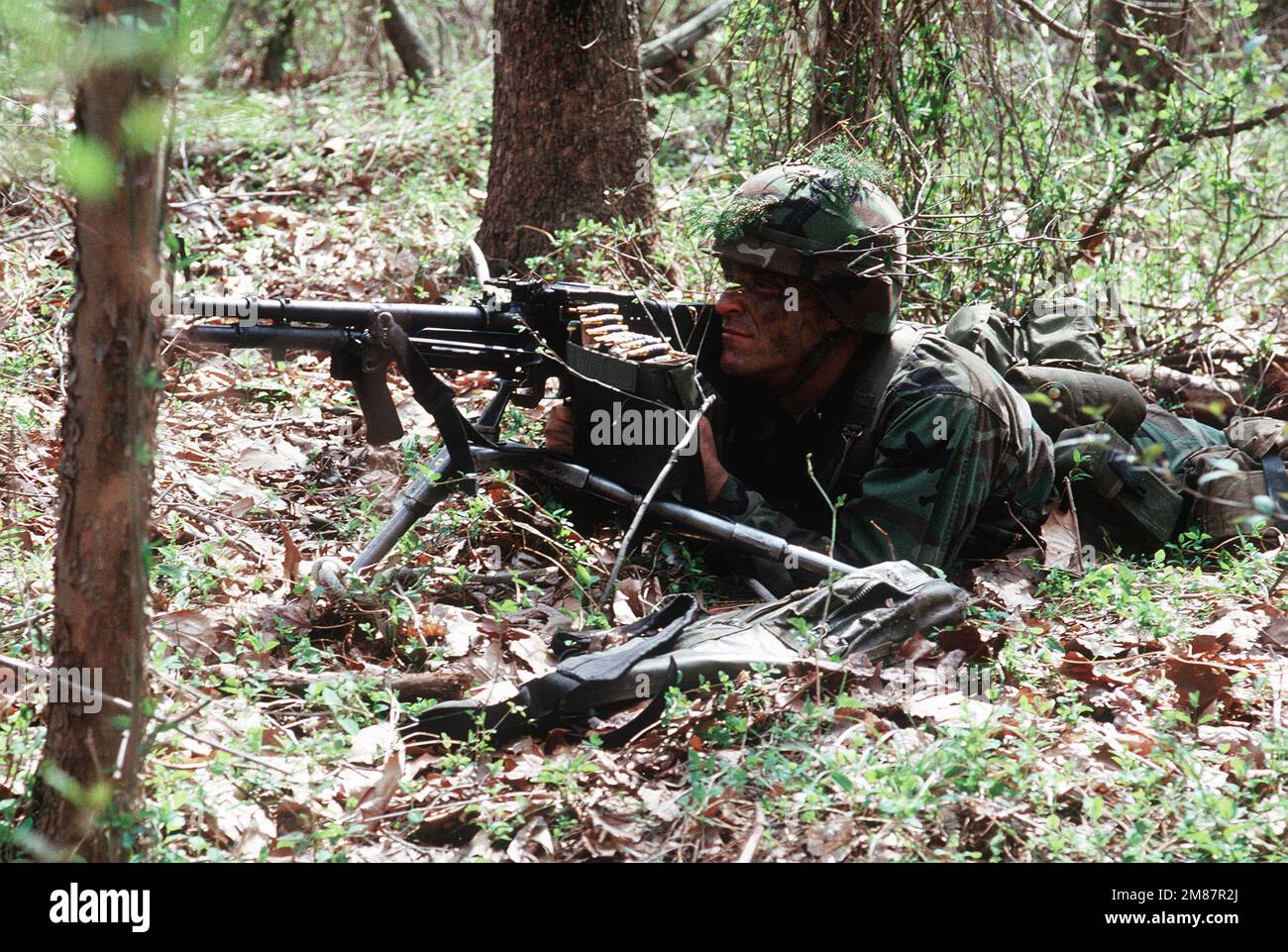 A camouflaged student aims his M-16A2 rifle from a prone position while ...